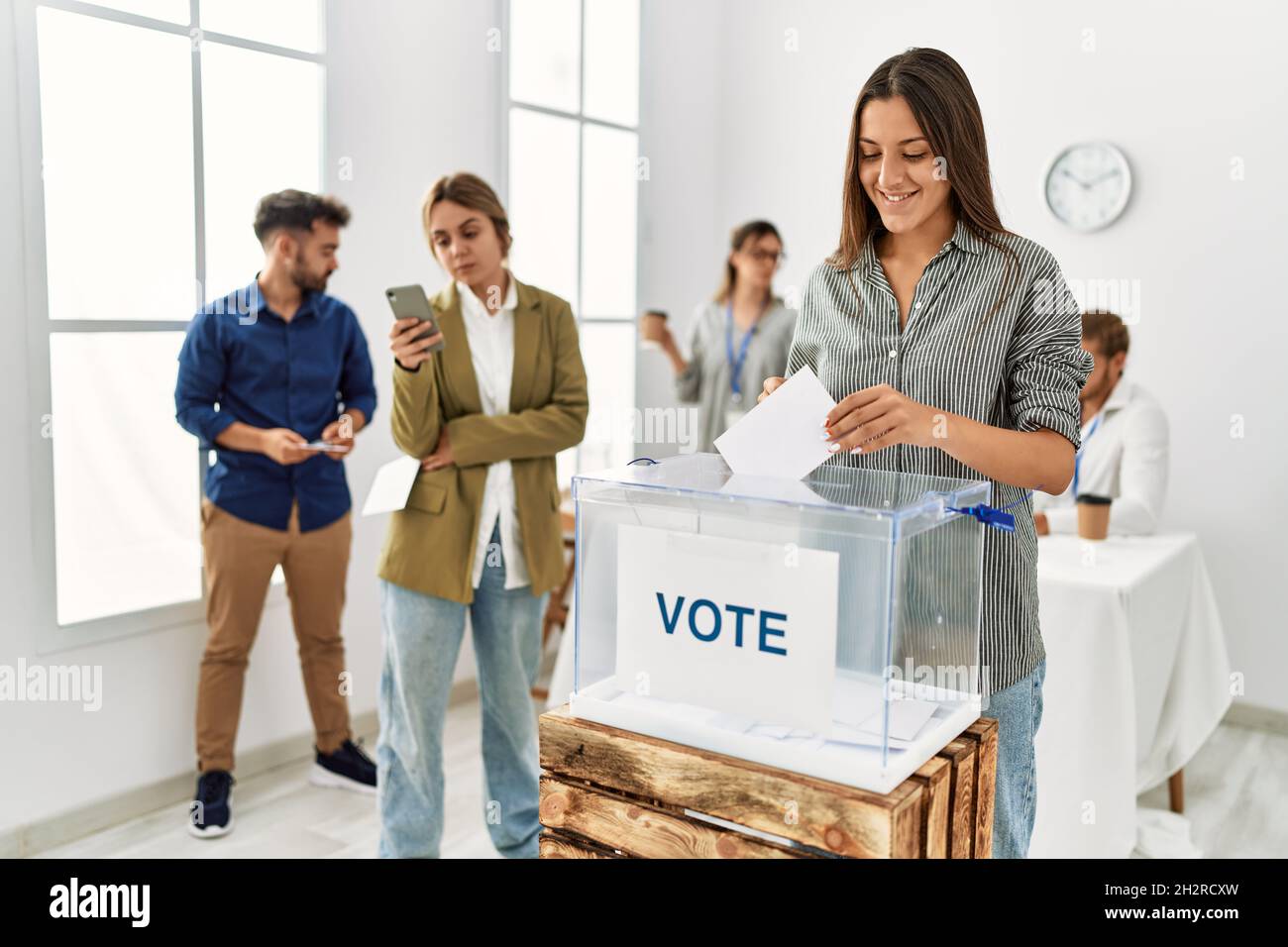 Young voter woman smiling happy putting vote in voting box at electoral ...