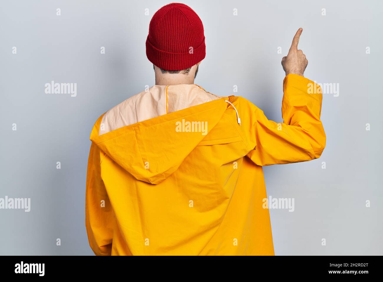 Caucasian man with beard wearing yellow raincoat posing backwards ...