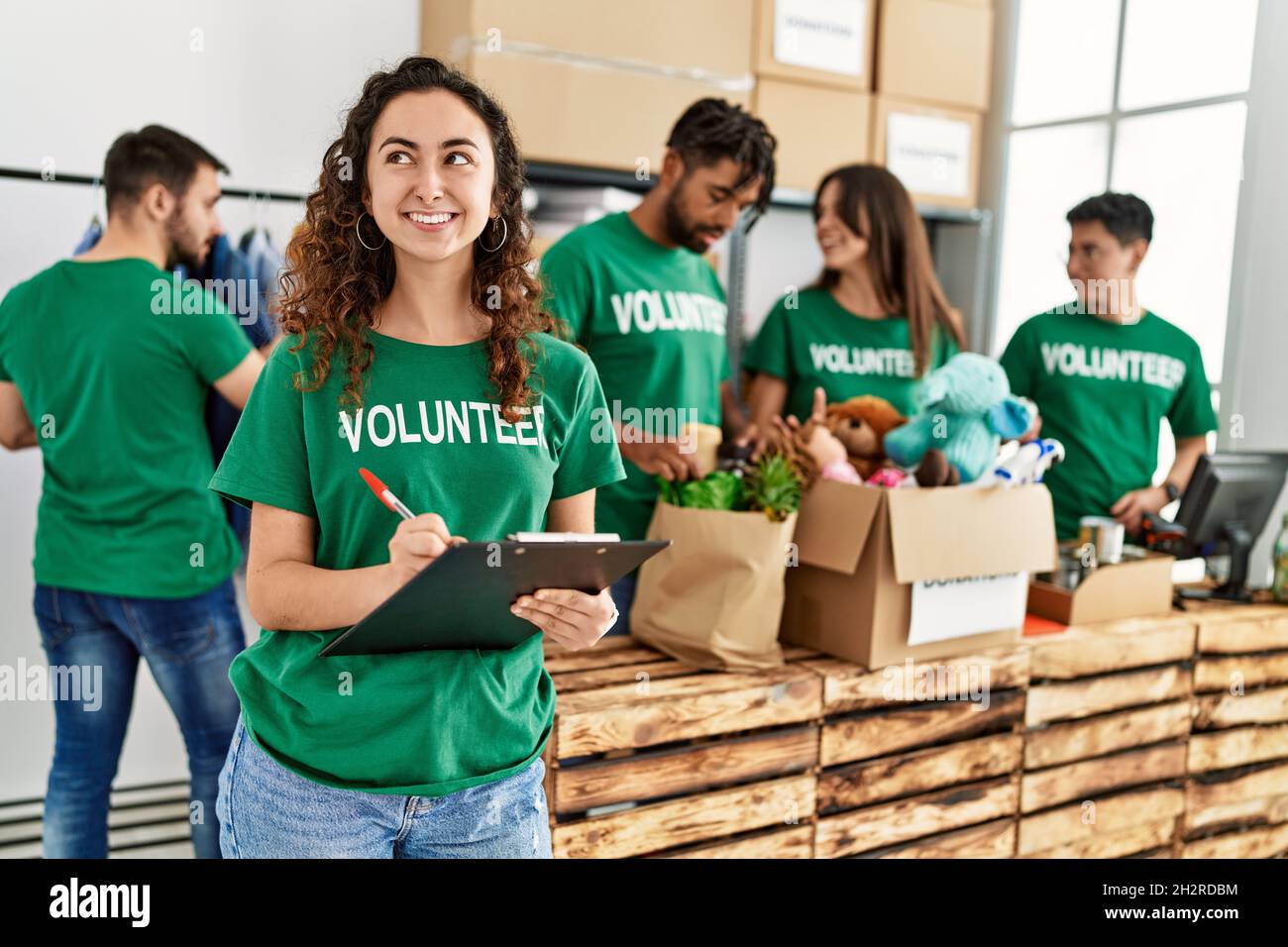 Group of young volunteers working at charity center. Woman smiling ...