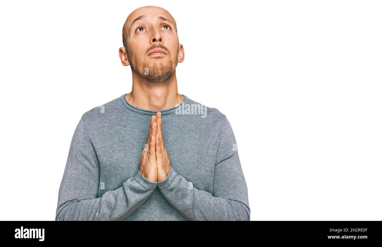 Bald man with beard wearing casual clothes begging and praying with ...