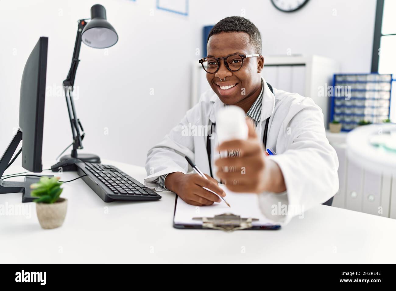 Young african man working as doctor writing pills prescription at ...