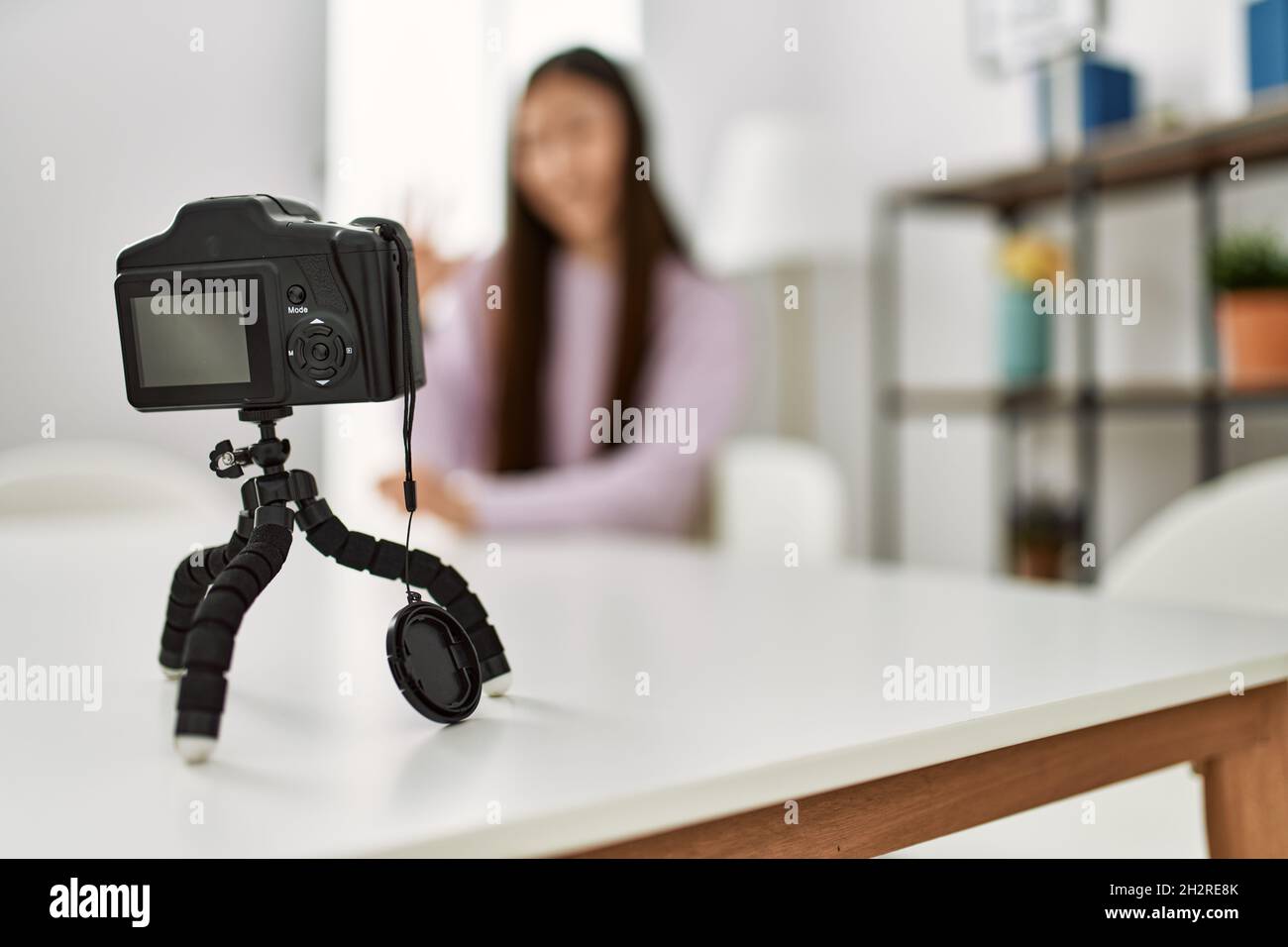 Young chinese girl having video call using camera sitting on the table ...