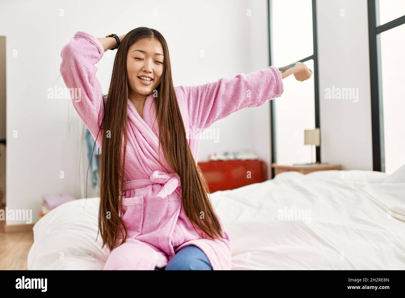 Young chinese girl waking up sitting on the bed at bedroom Stock Photo ...