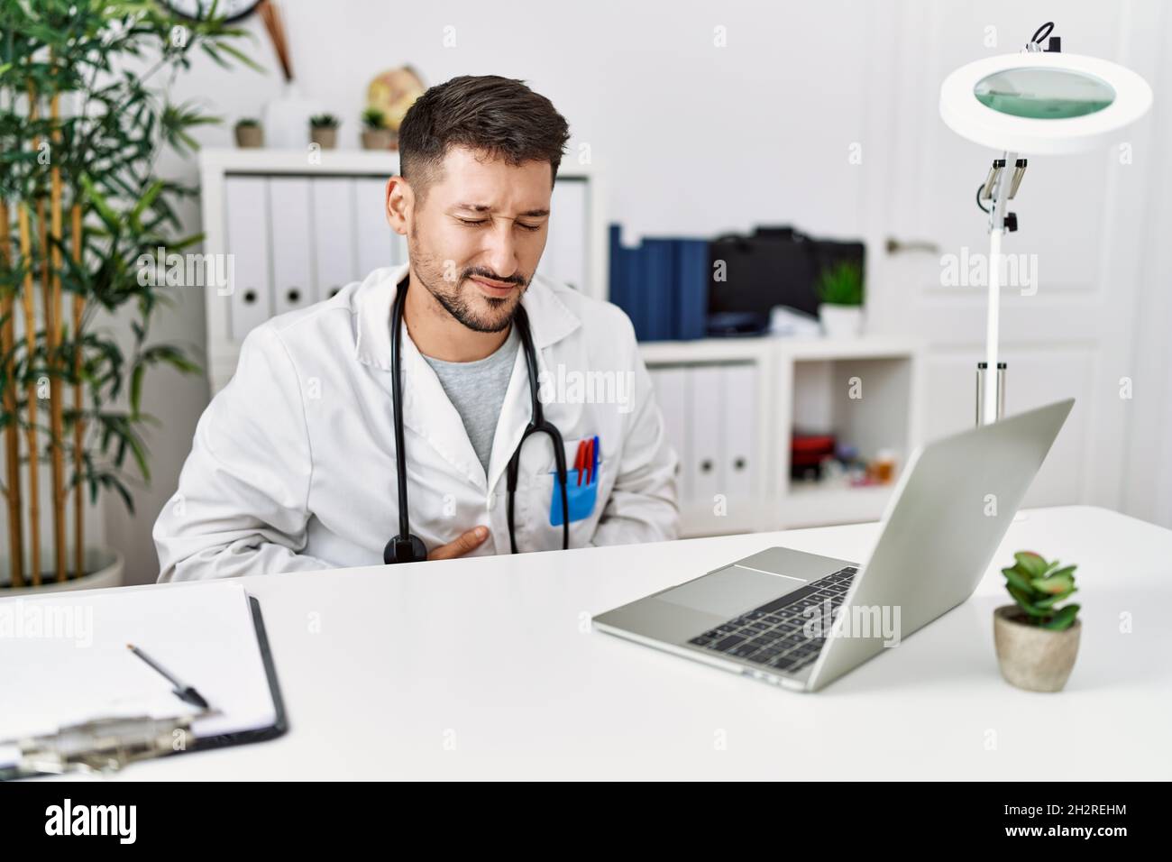 Young doctor working at the clinic using computer laptop with hand on ...