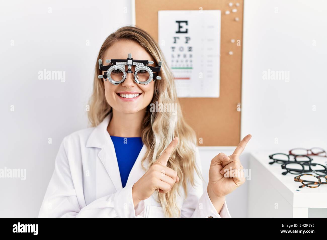 Young beautiful optician woman wearing optometry glasses at the clinic ...