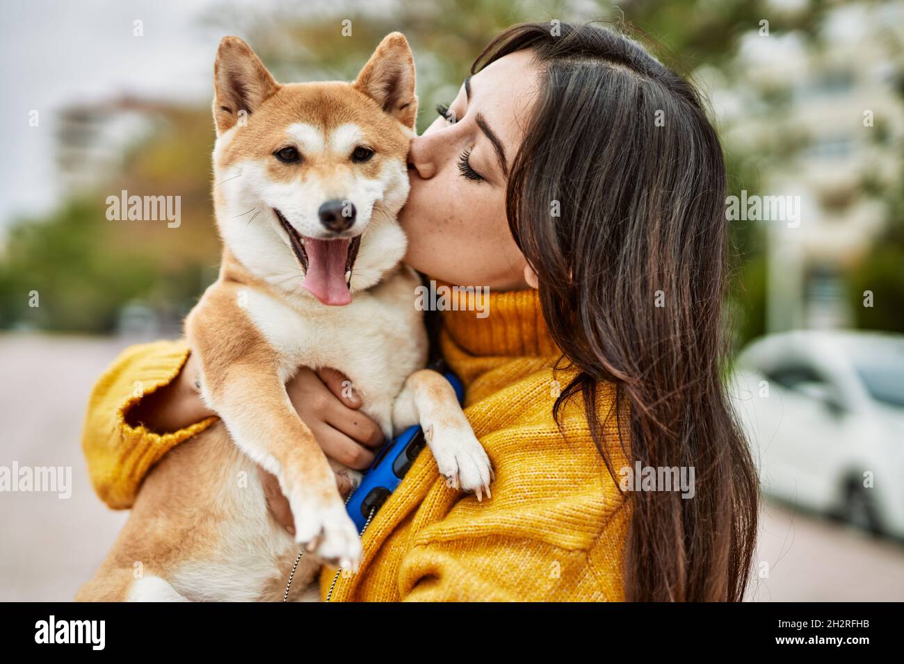 Beautiful young woman kissing and hugging shiba inu dog at street Stock ...