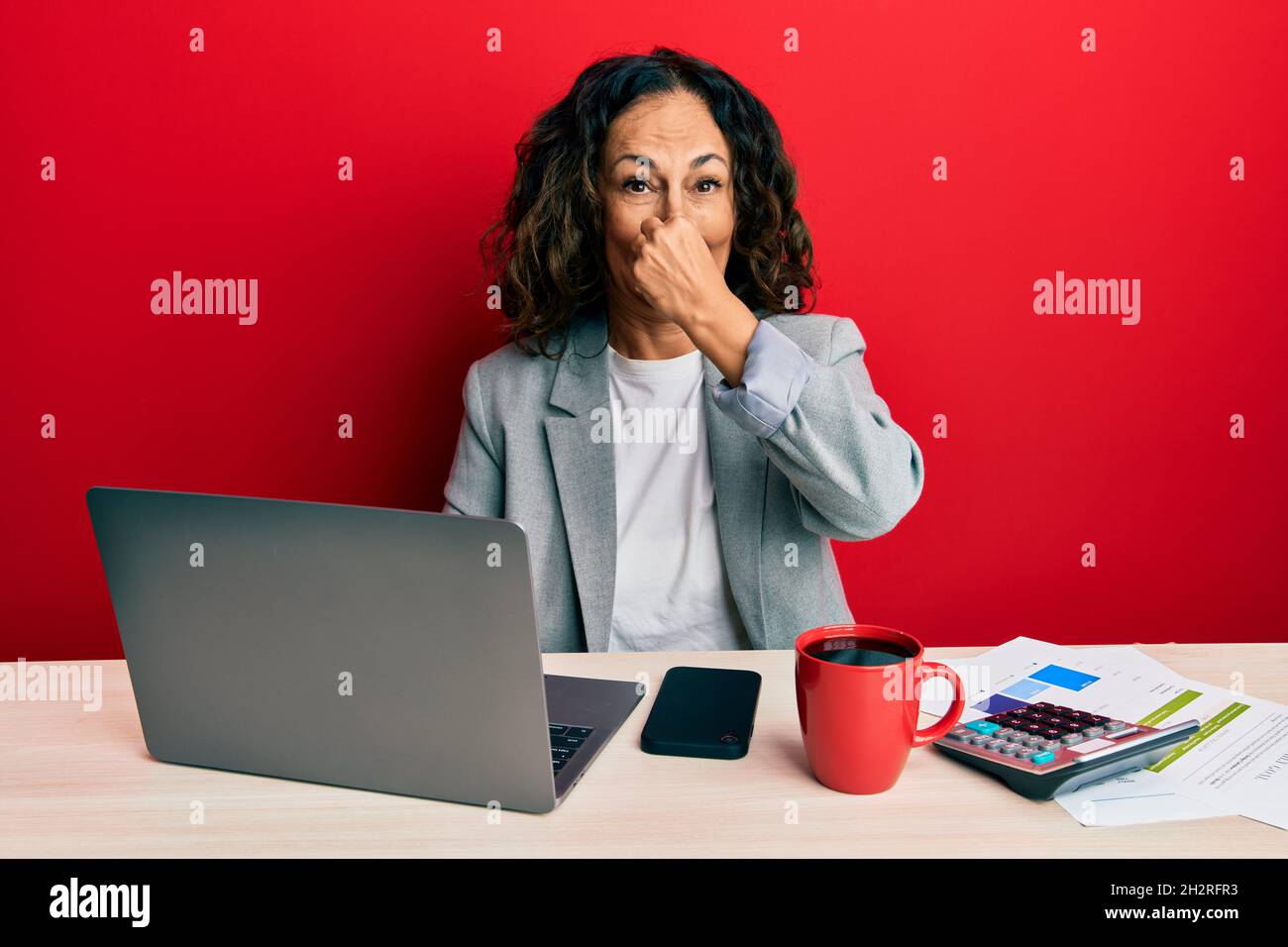 Beautiful middle age woman working at the office drinking a cup of ...
