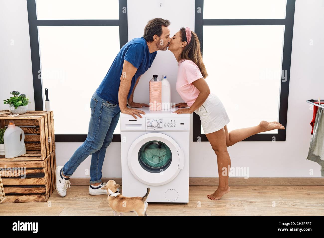 Middle age man and woman couple kissing and washing clothes at laundry ...