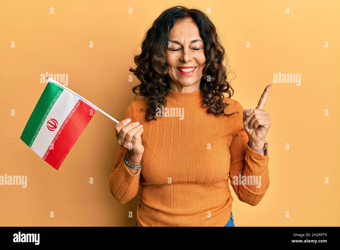 Middle age hispanic woman holding iran flag smiling happy pointing with ...