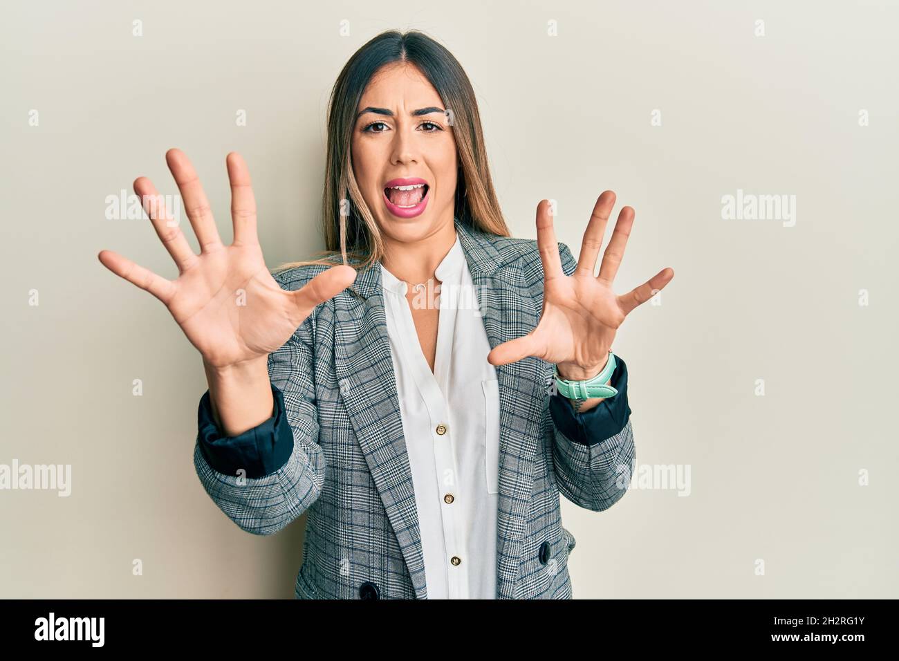 Young hispanic woman wearing business clothes afraid and terrified with ...