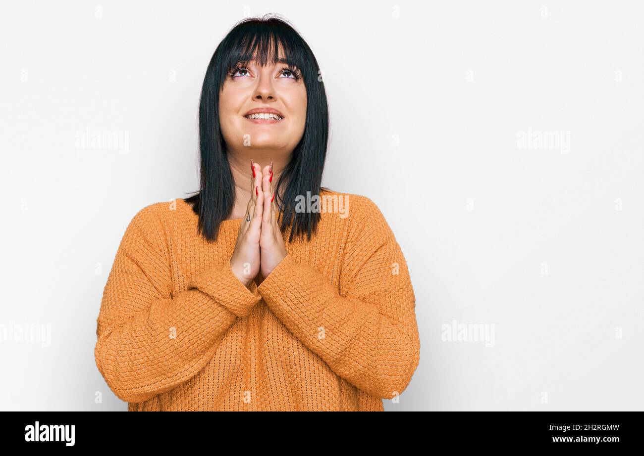 Young hispanic woman wearing casual clothes begging and praying with ...