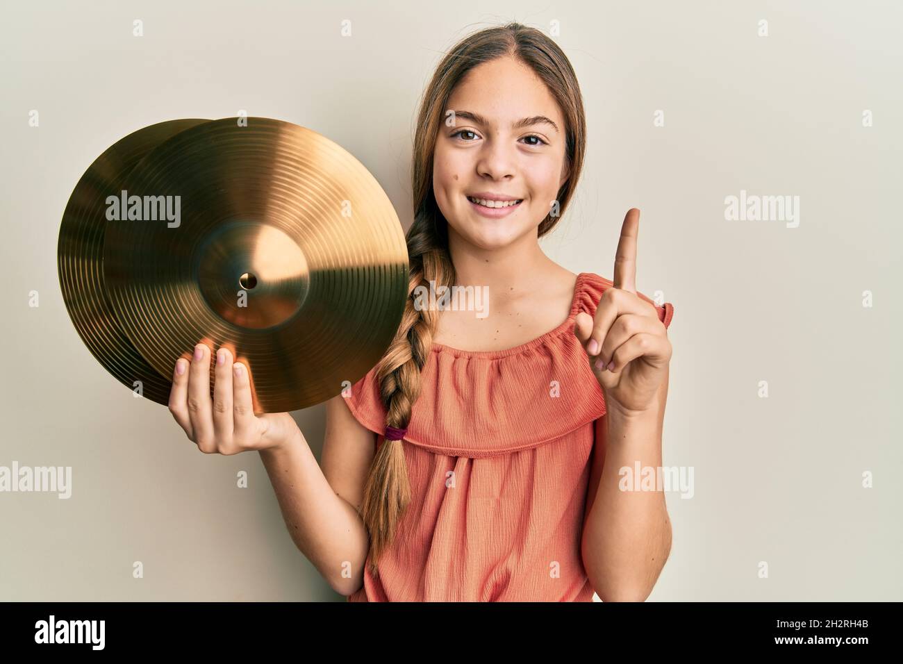 Beautiful brunette little girl holding golden cymbal plates smiling ...