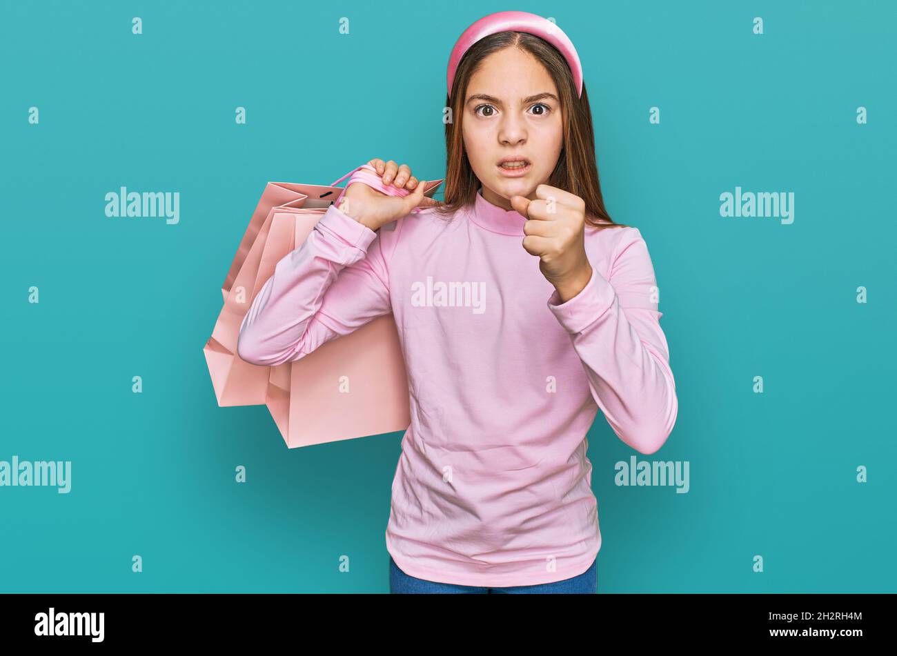 Beautiful brunette little girl holding shopping bags annoyed and ...