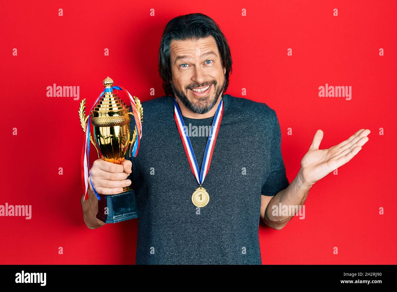 Middle age caucasian man holding champion trophy wearing medals ...
