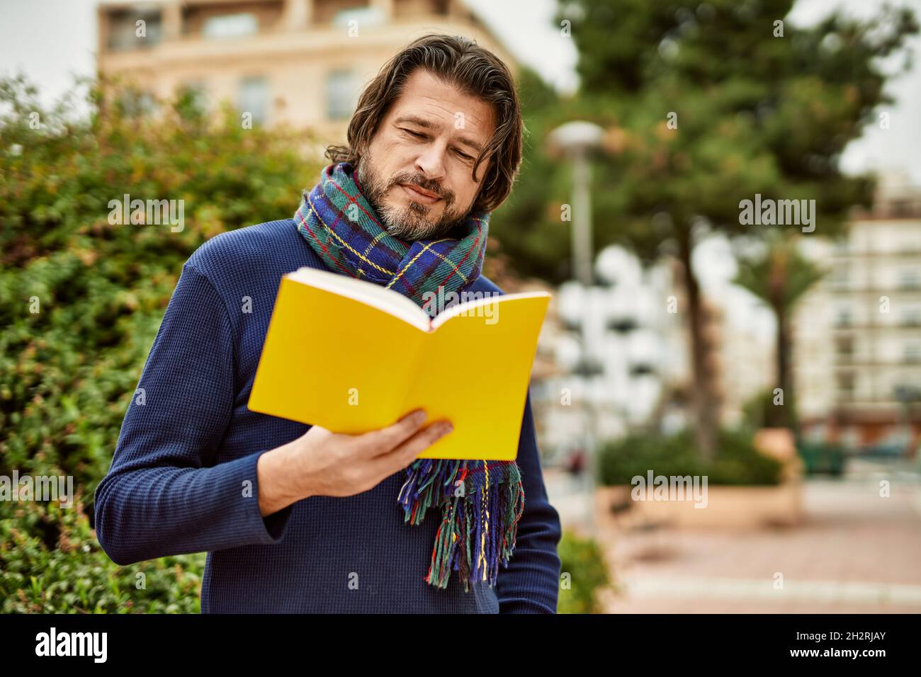 Middle age handsome man reading a book outdoors at the park Stock Photo ...