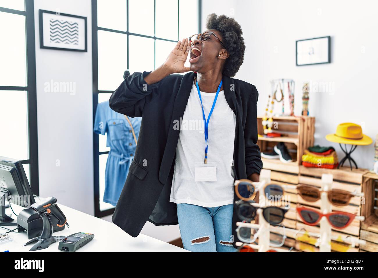 African young woman working as manager at retail boutique shouting and ...