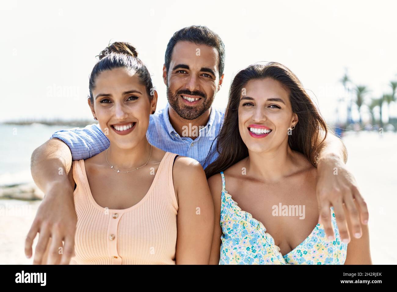 Three young hispanic friends smiling happy and hugging at the beach ...