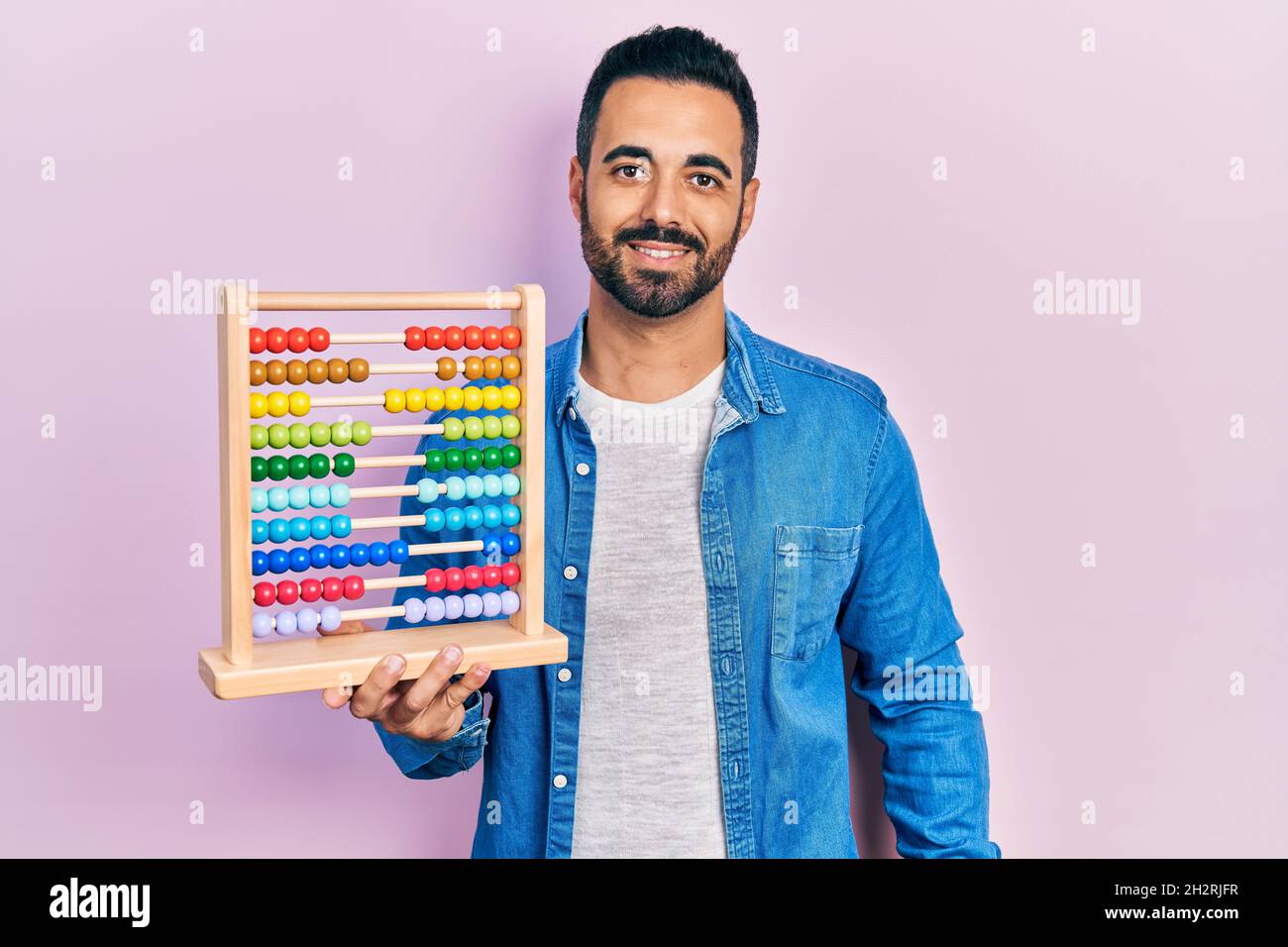 Handsome hispanic man with beard holding traditional abacus looking ...