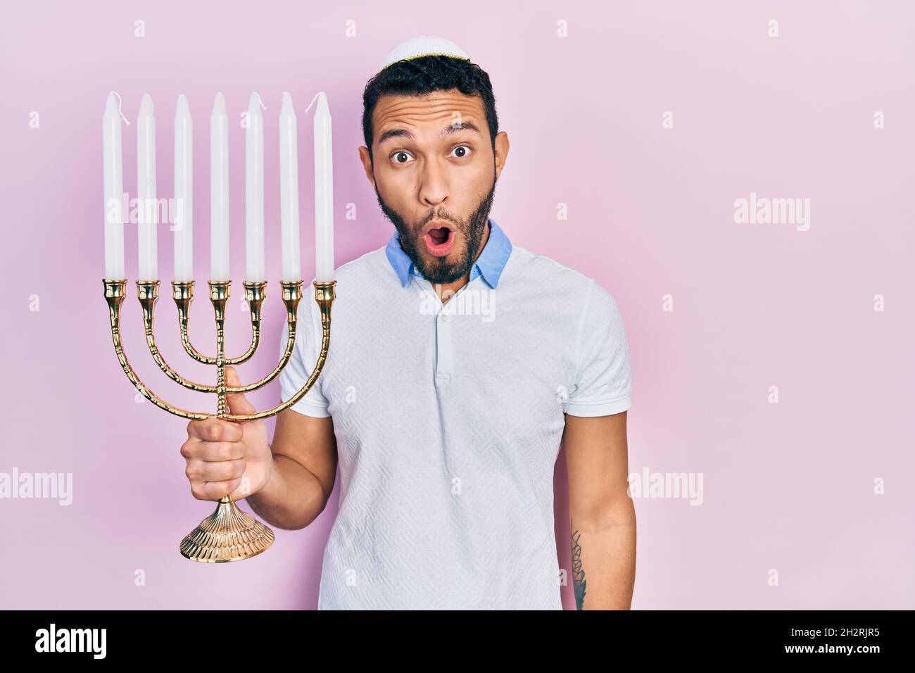 Hispanic man with beard holding menorah hanukkah jewish candle scared ...