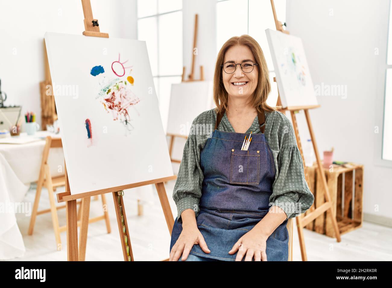 Middle age artist woman at art studio with a happy and cool smile on ...