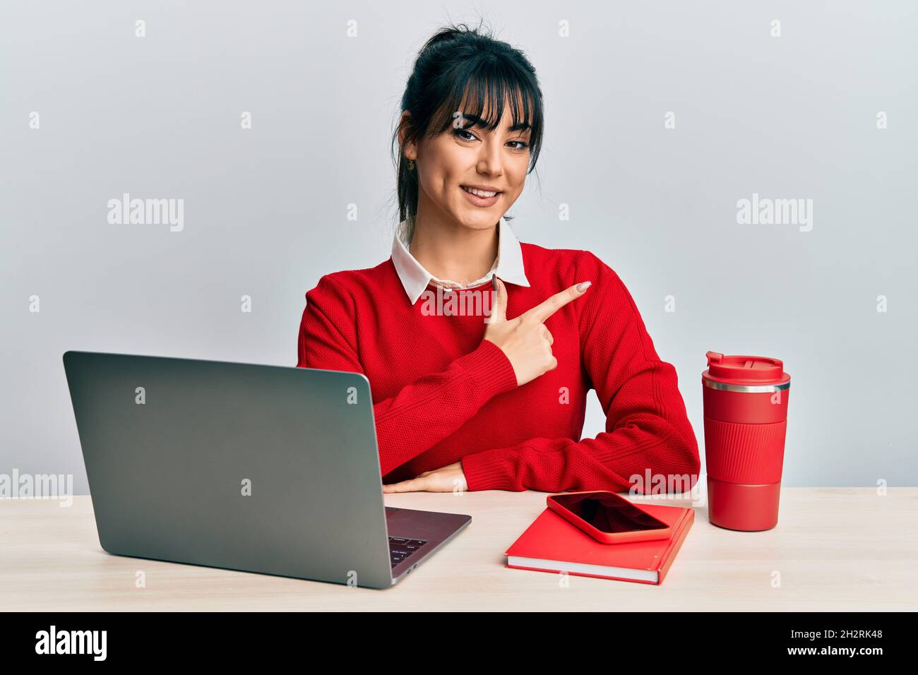 Young brunette woman with bangs working at the office with laptop ...