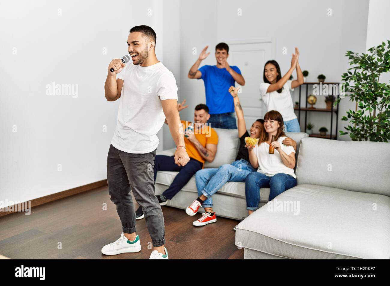 Group of young friends having party singing song using microphone at ...