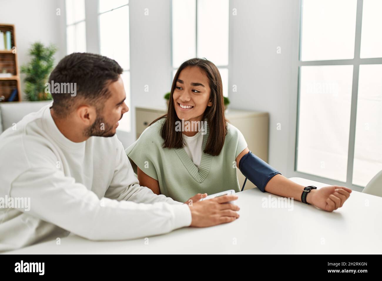 Young latin couple smiling happy measuring blood pressure using ...