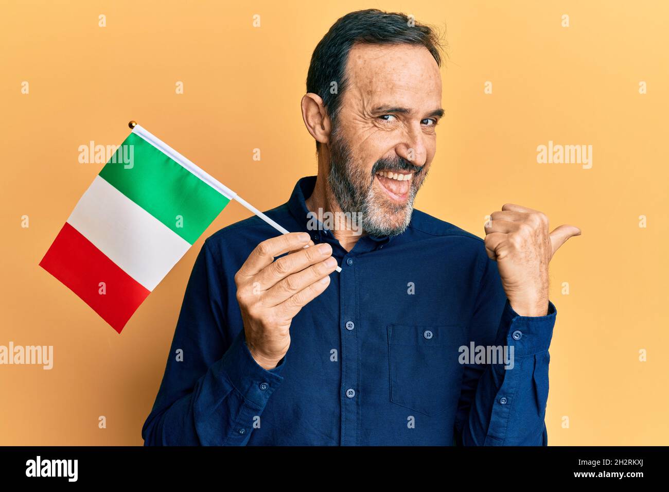 Middle age hispanic man holding italy flag pointing thumb up to the ...