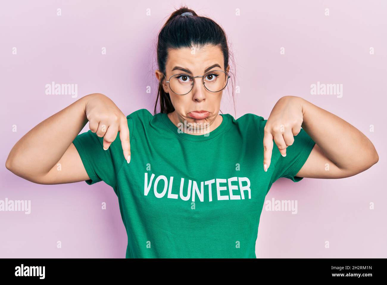 Young hispanic woman wearing volunteer t shirt pointing down looking ...