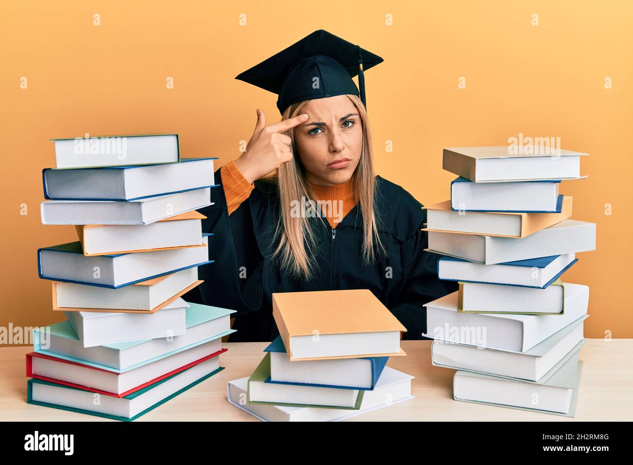 Young caucasian woman wearing graduation ceremony robe sitting on the ...