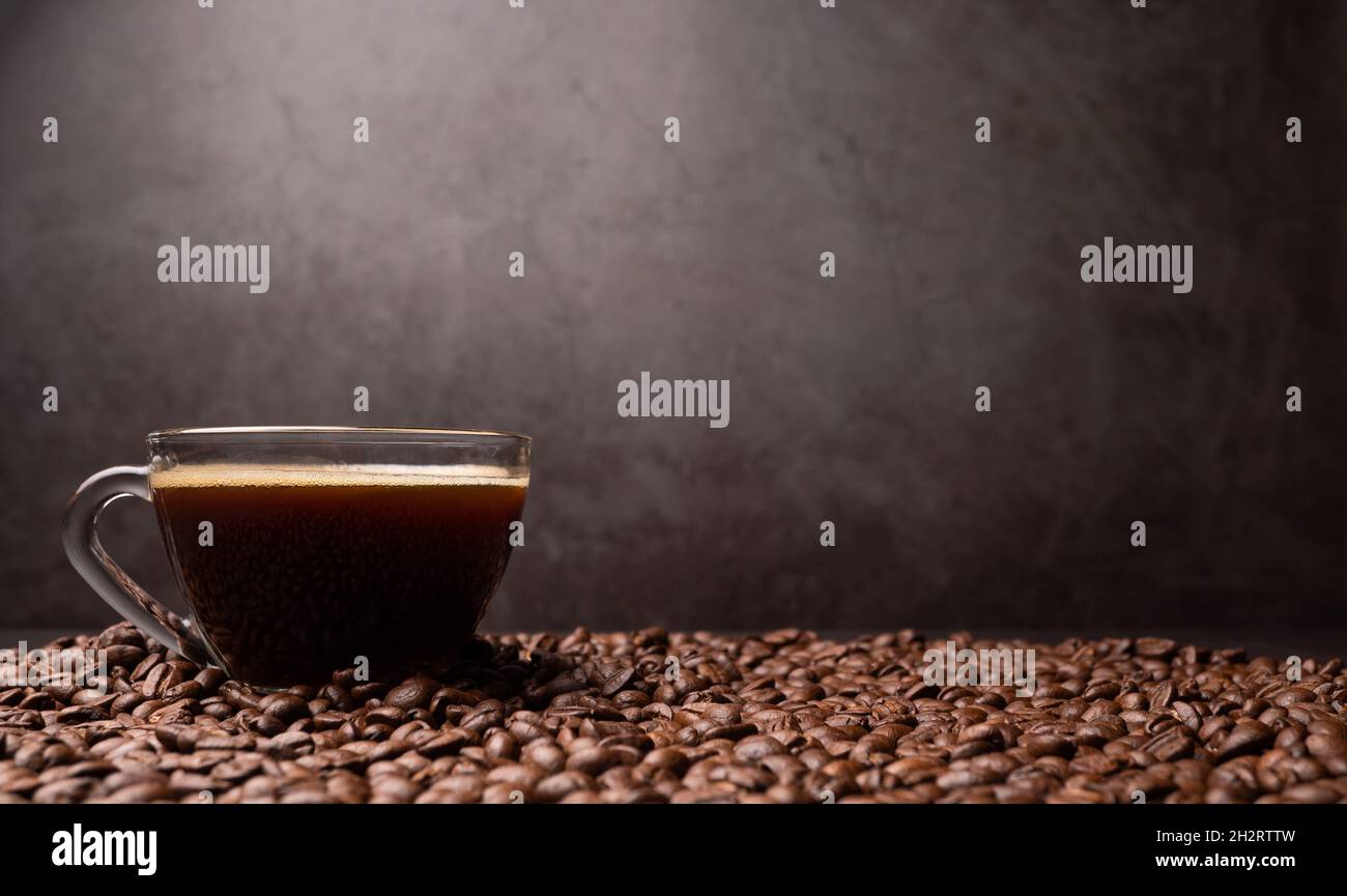 The side view of a coffee cup and group of black coffee beans is the ...