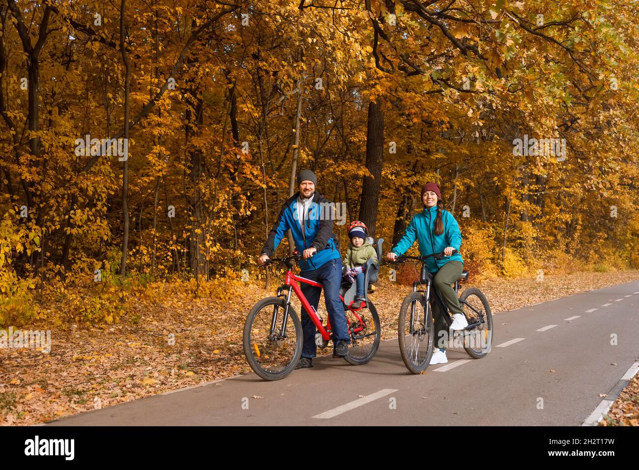 family with child riding on bikes together in autumn park Stock Photo ...