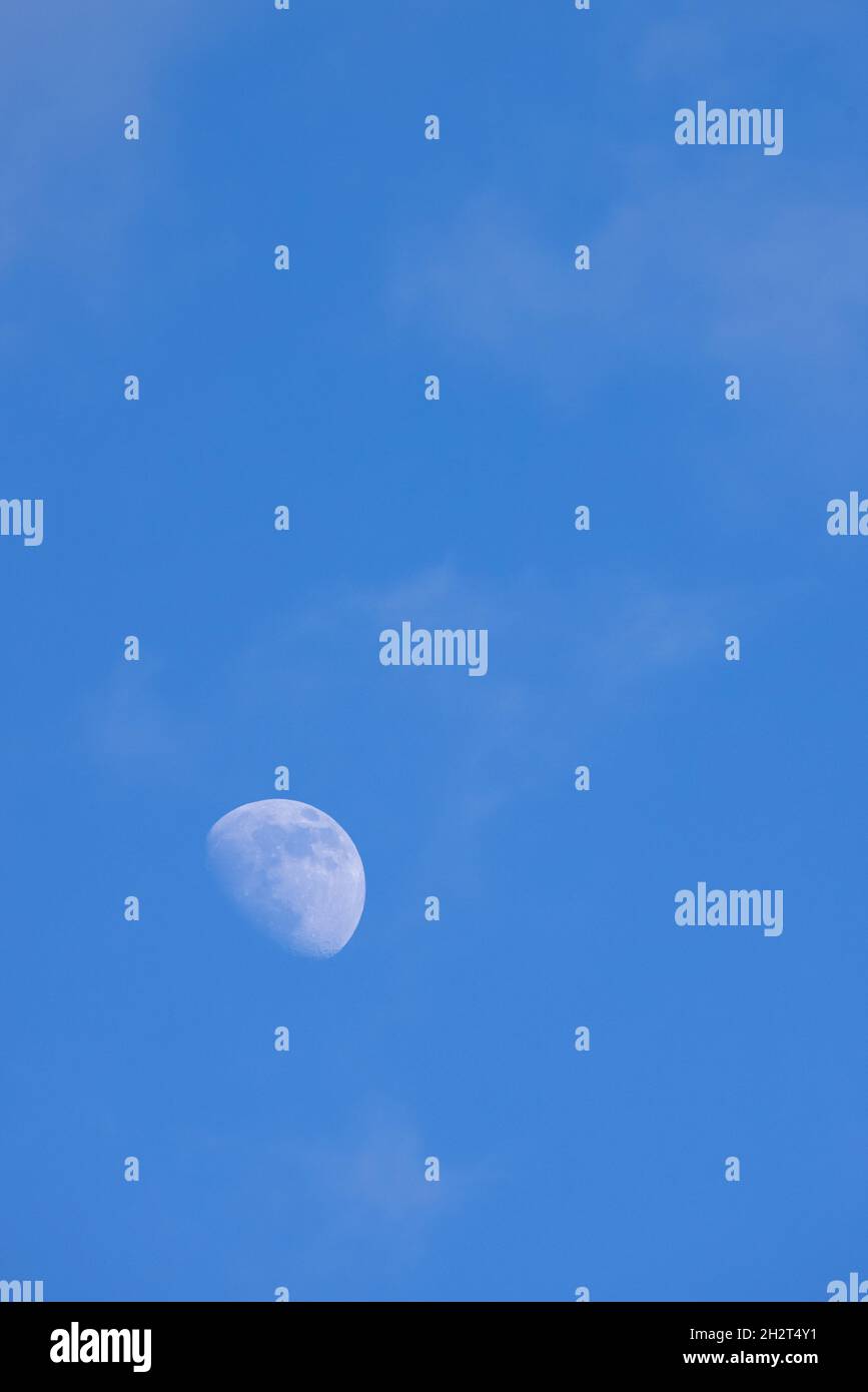 Partial moon against blue sky with light clouds Stock Photo - Alamy