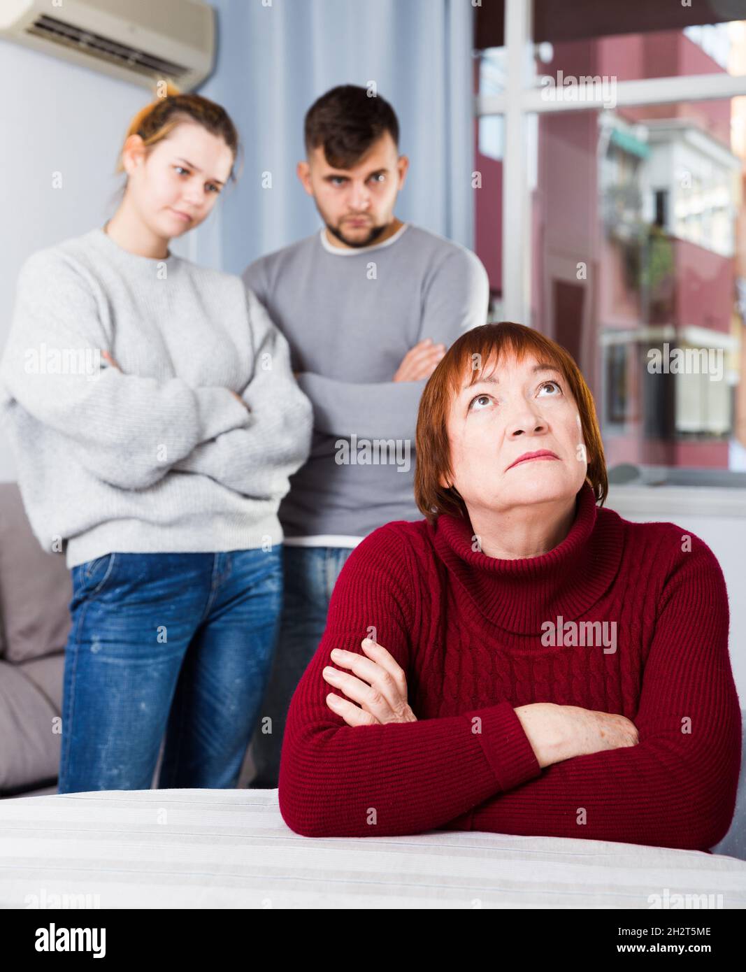 Chagrined senior woman in quarrel with young couple Stock Photo - Alamy