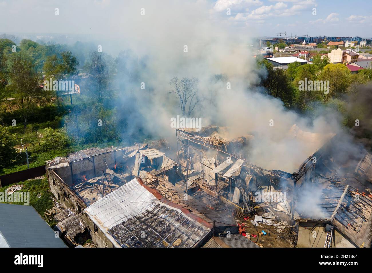 Aerial view of ruined building on fire with collapsed roof and rising ...