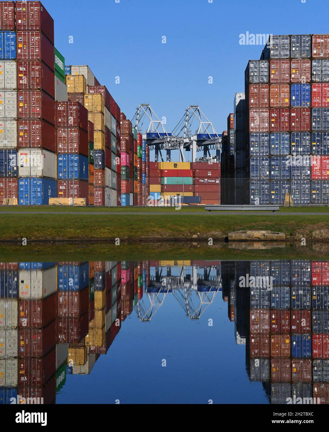 Shipping containers are seen reflected in a pond at the Port of ...