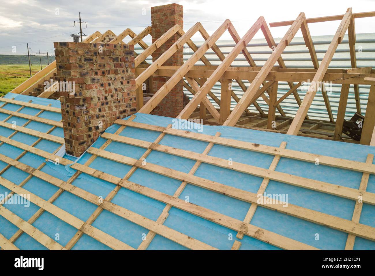 Aerial view of a brick house with wooden roof frame under construction ...