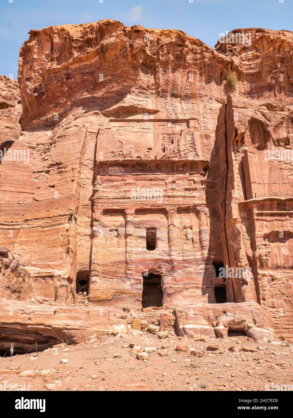 Detail with the ancient burial chambers carved in red sandstone cliffs ...