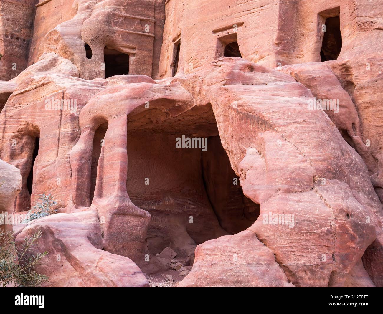 Ancient housing carved in red sand rock in the city of Petra, Jordan ...