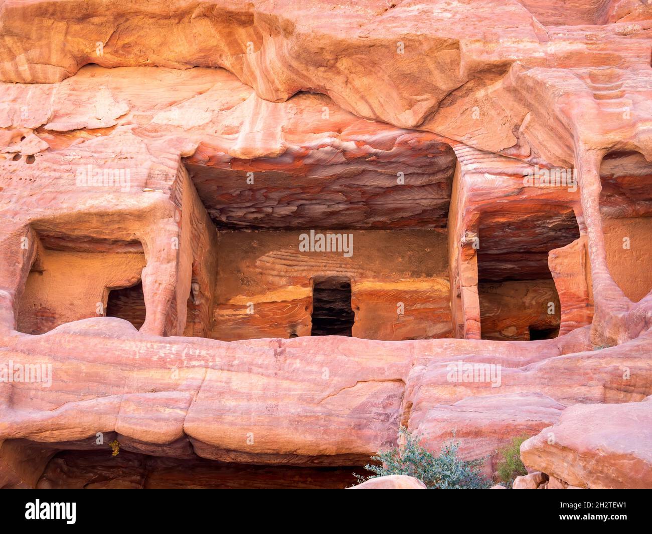 Ancient housing carved in red sand rock in the city of Petra, Jordan ...