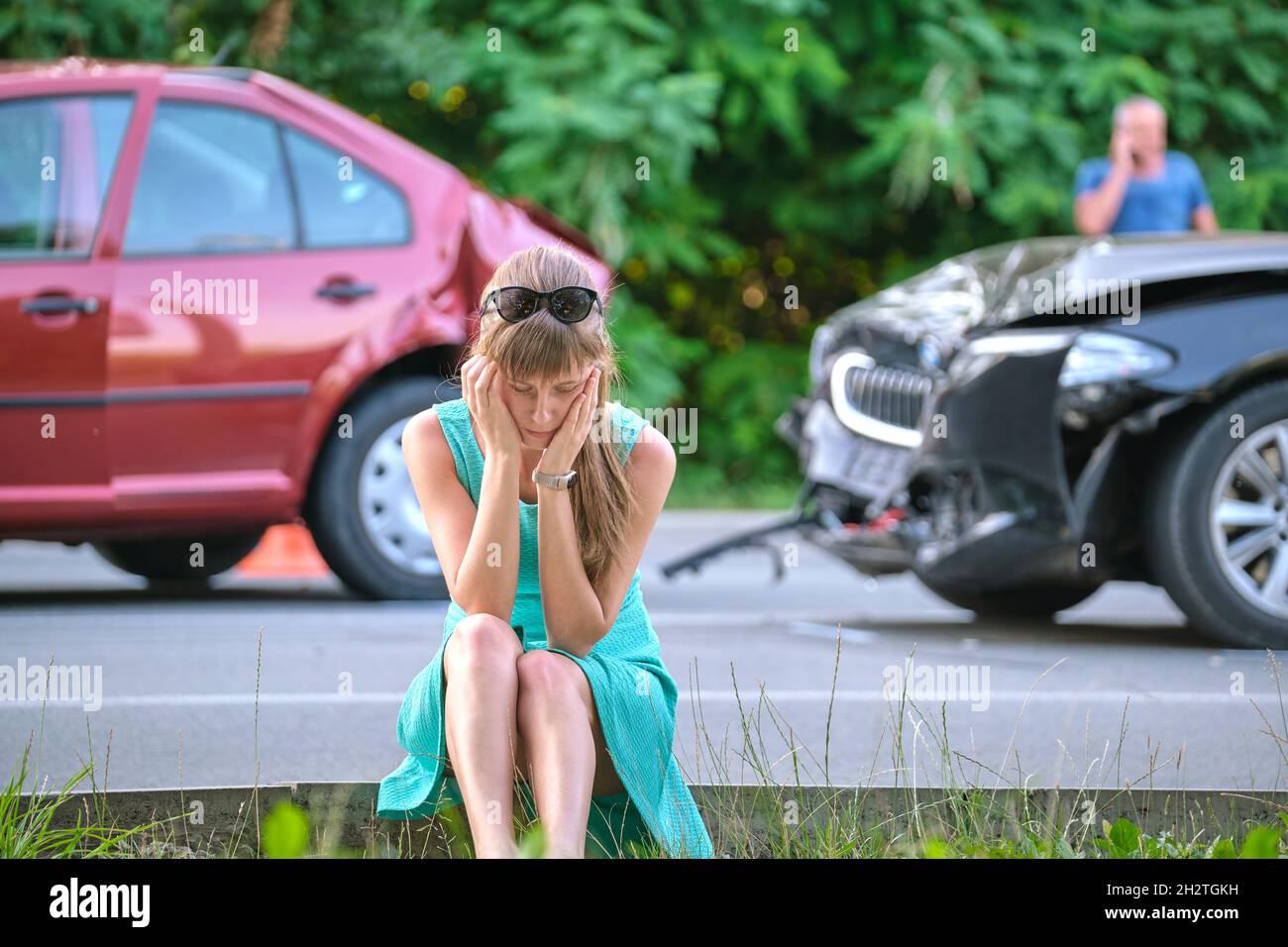 Sad female driver sitting on street side shocked after car accident ...