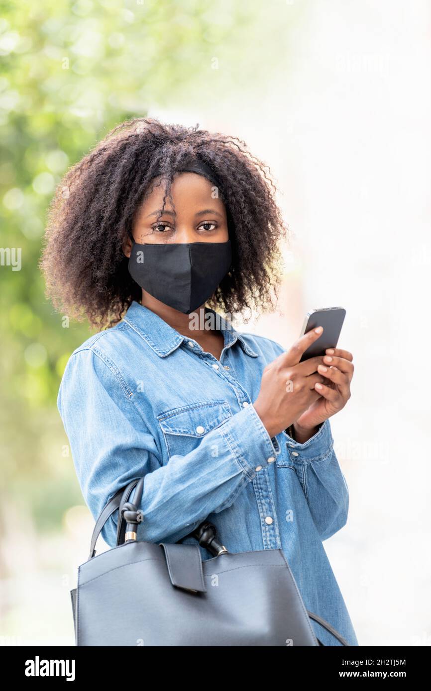 Vertical photo of an afro woman using the mobile while covering the ...