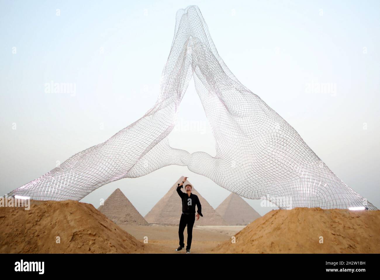 Italian artists, Lorenzo Quinn, poses under his installation, entitled ...