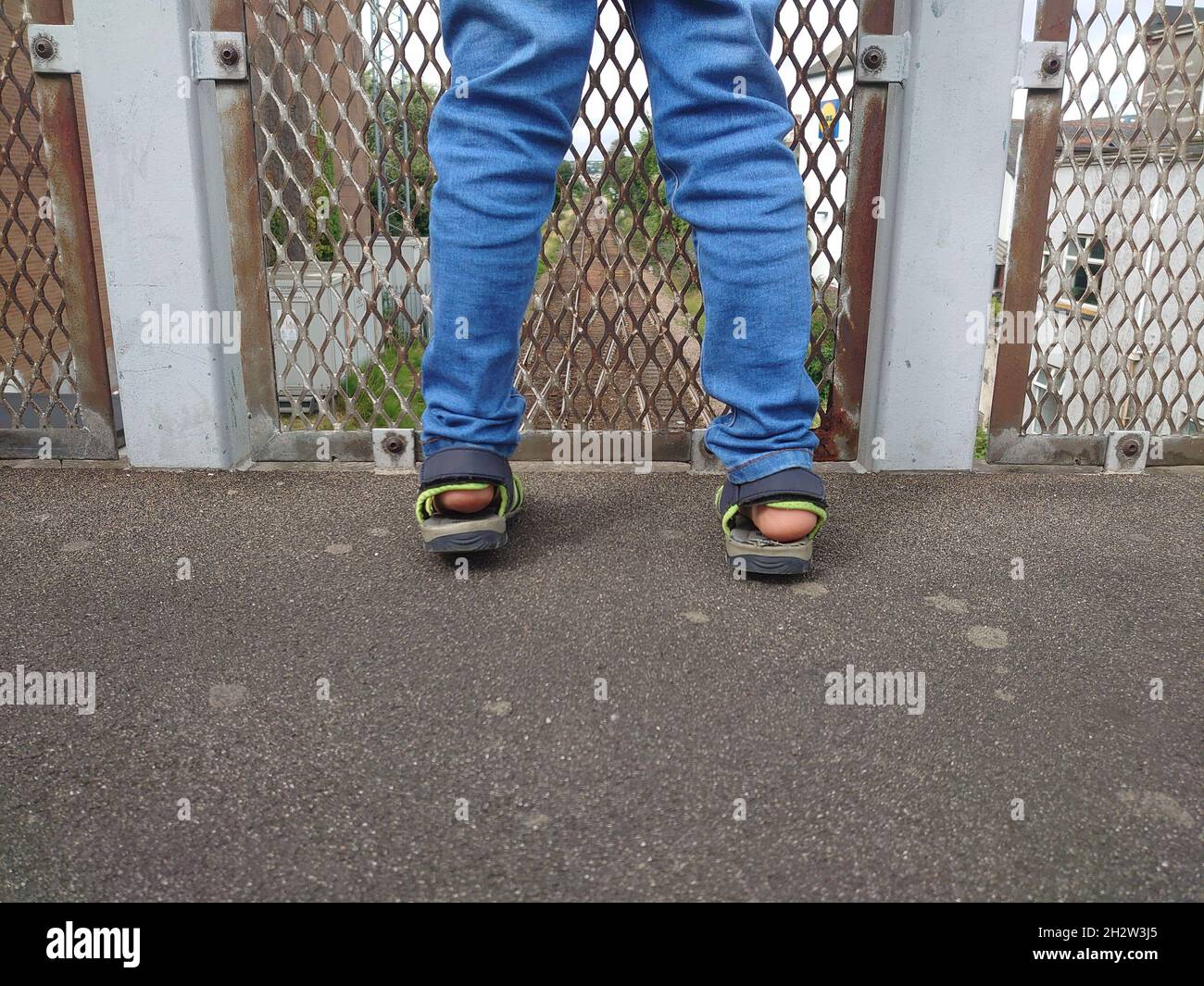 The legs of a kid standing by the meshed metal door Stock Photo - Alamy