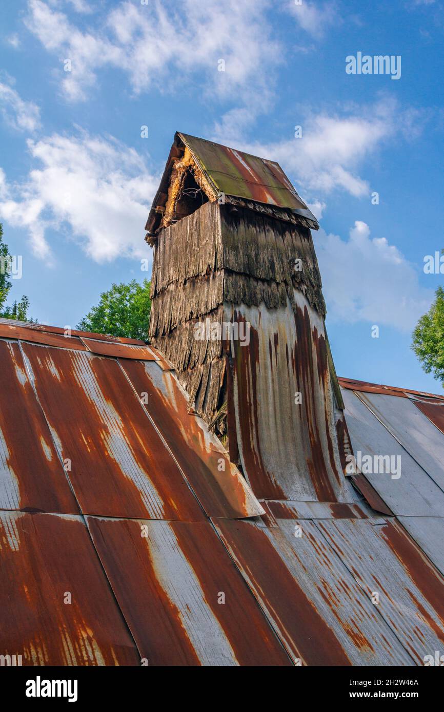 View of old house roof, covered with rusty steel sheets and chimney ...