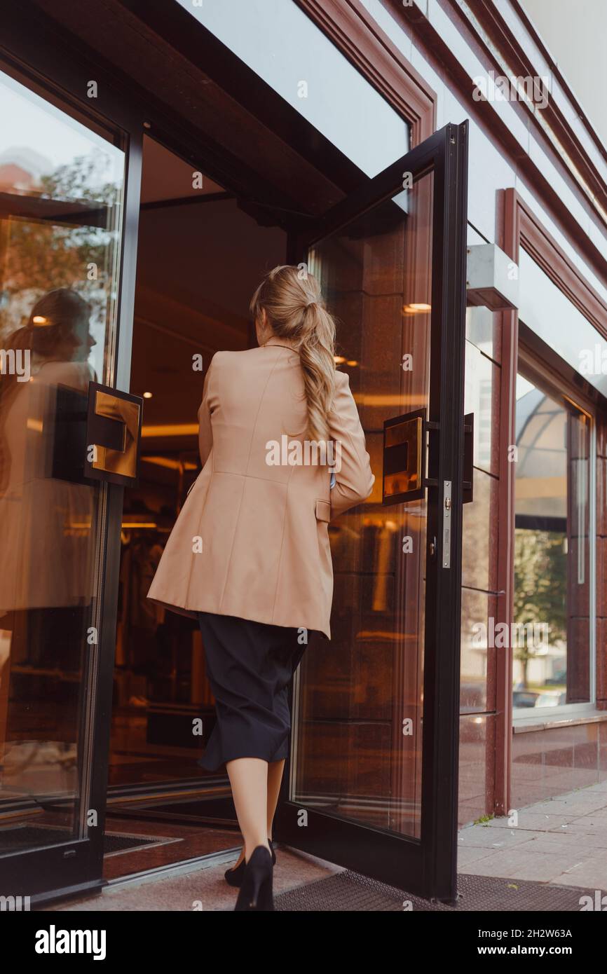 Young elegant dressed woman entering the building, back view, summer ...