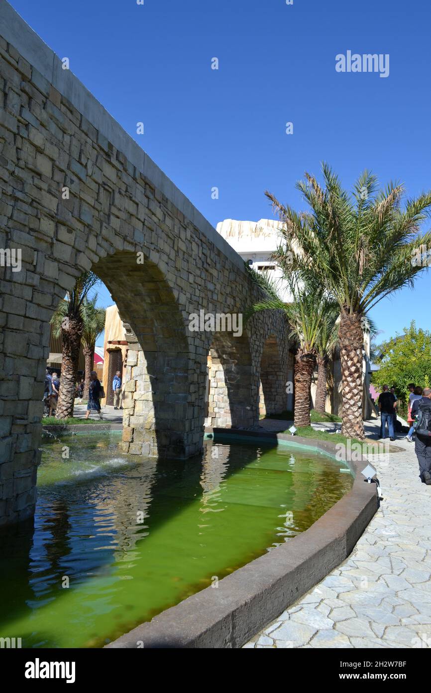 Beautiful oasis landscape of the Oman pavilion. Pool with blue water ...