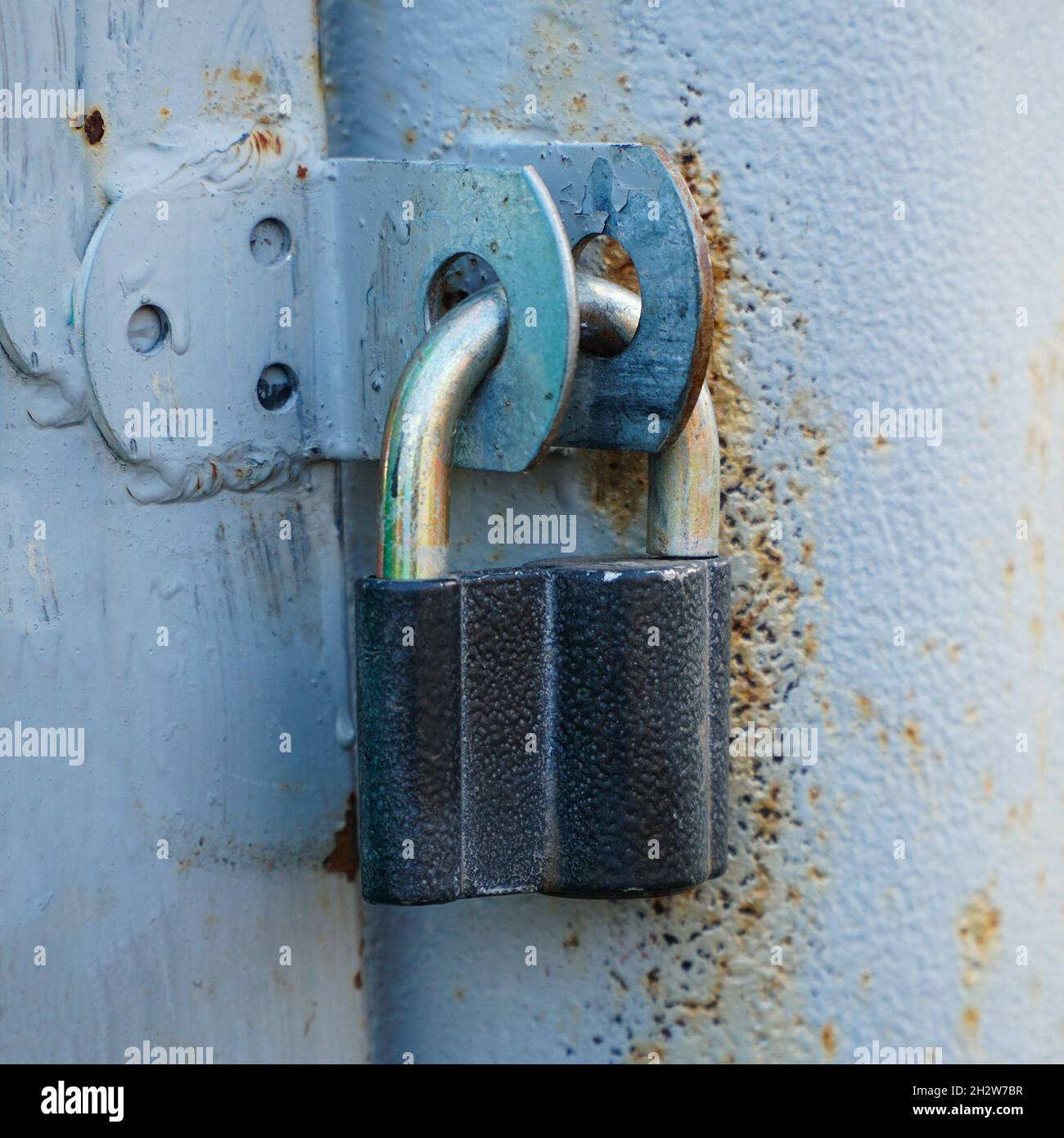 Closed padlock hanging on the hinges on the gray iron door Stock Photo ...