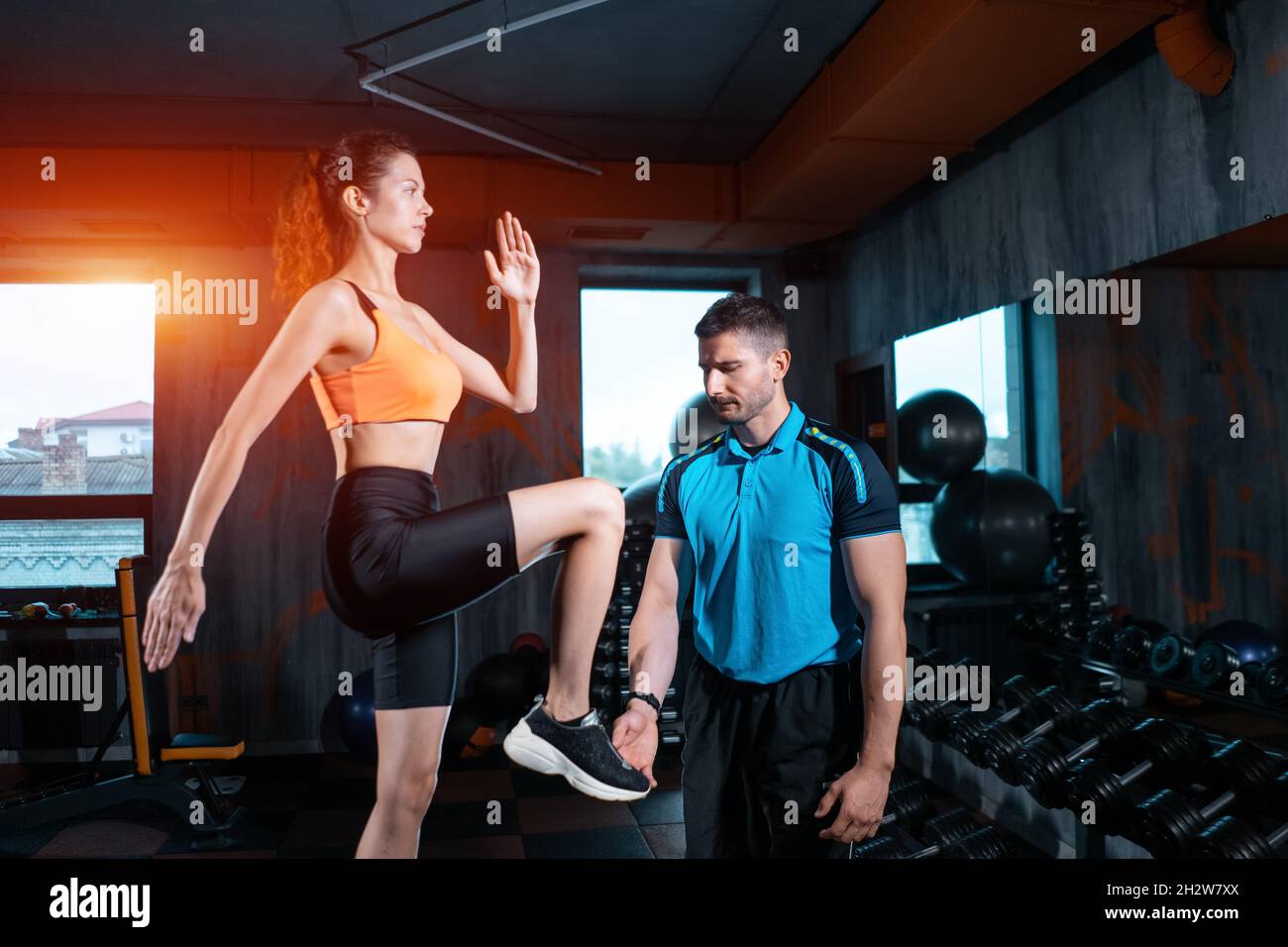 athlete female has exercising lunges on step box with personal trainer ...