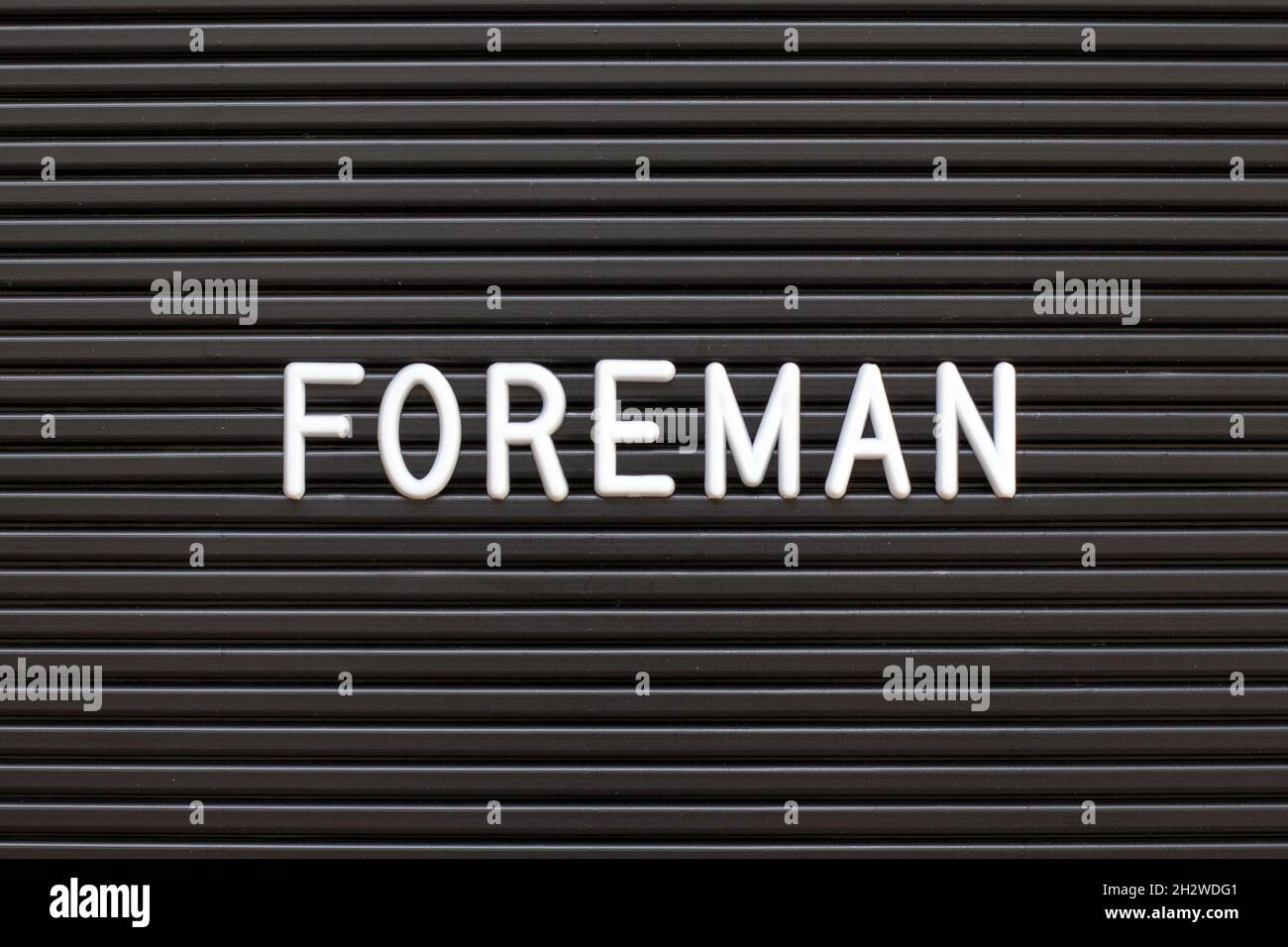 White alphabet in word foreman on black color felt letter board ...